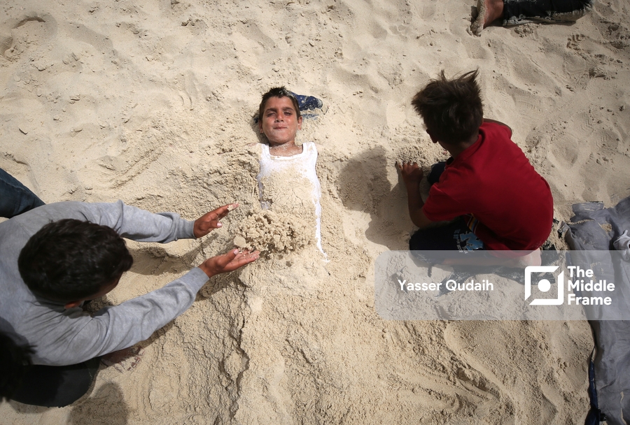 Palestinian children playing in the sand on the beach of Rafah city ...