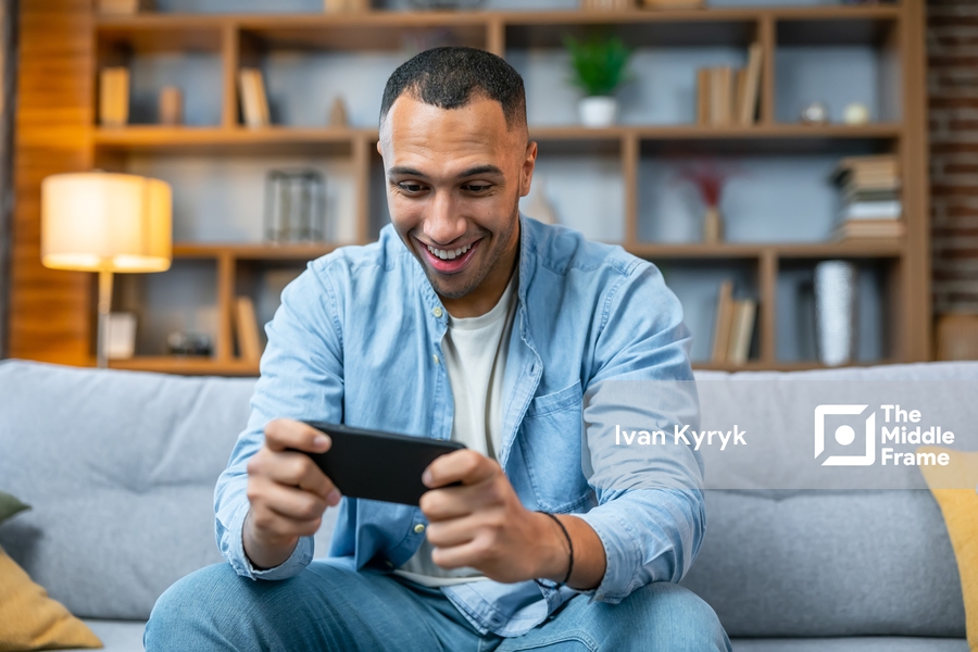 Excited gamer playing a mobile game • The Middle Frame • Arab Stock ...